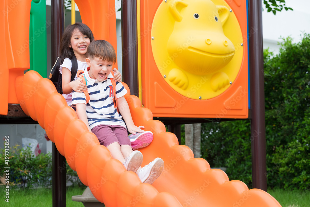 Two kids friends having fun to play together on children's slide at ...