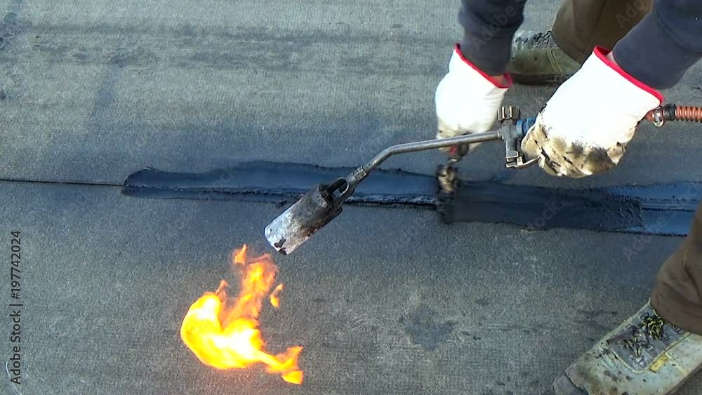 Worker performs sealing overlapping bitumen sheets on the flat roof of ...