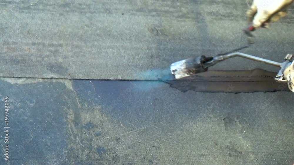 Worker performs sealing overlapping bitumen sheets on the flat roof of ...