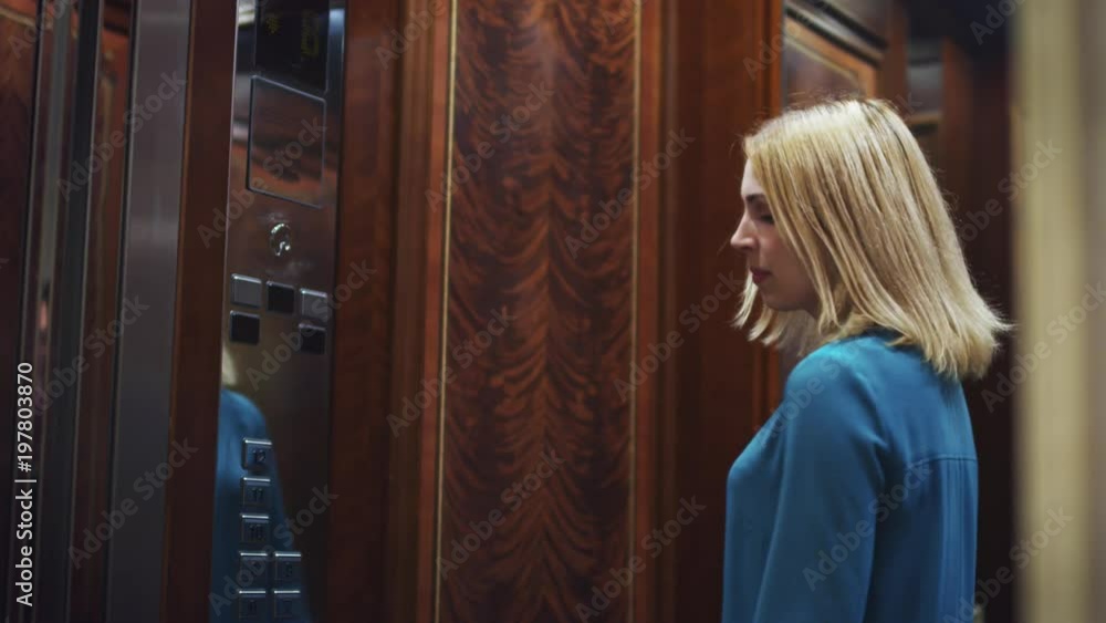 Opening mirror lift doors and young woman coming into elevator car ...