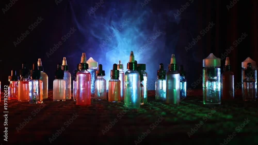 Vape concept. Slider shot. Smoke clouds and vape liquid bottles on dark ...