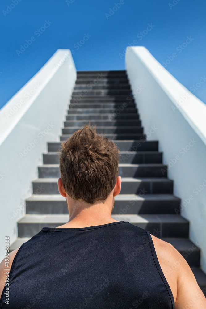Runner going up stairs running challenge. Fitness man looking ahead at ...