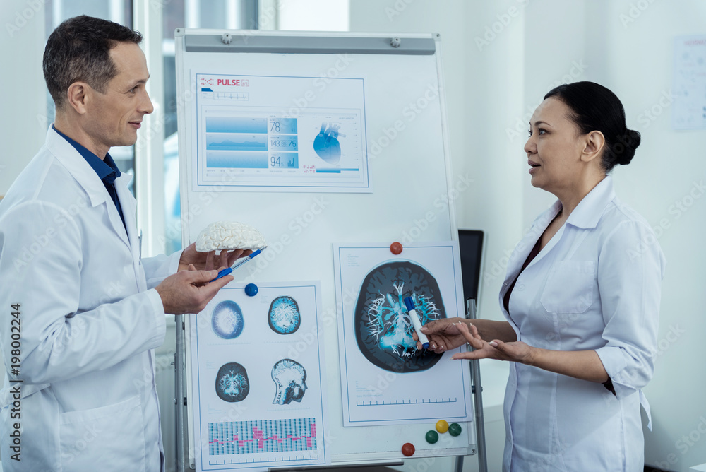 Brainstorming. Professional scientists looking at brain image while ...