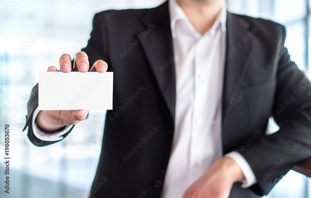 Casual business man holding empty white business card in modern office ...