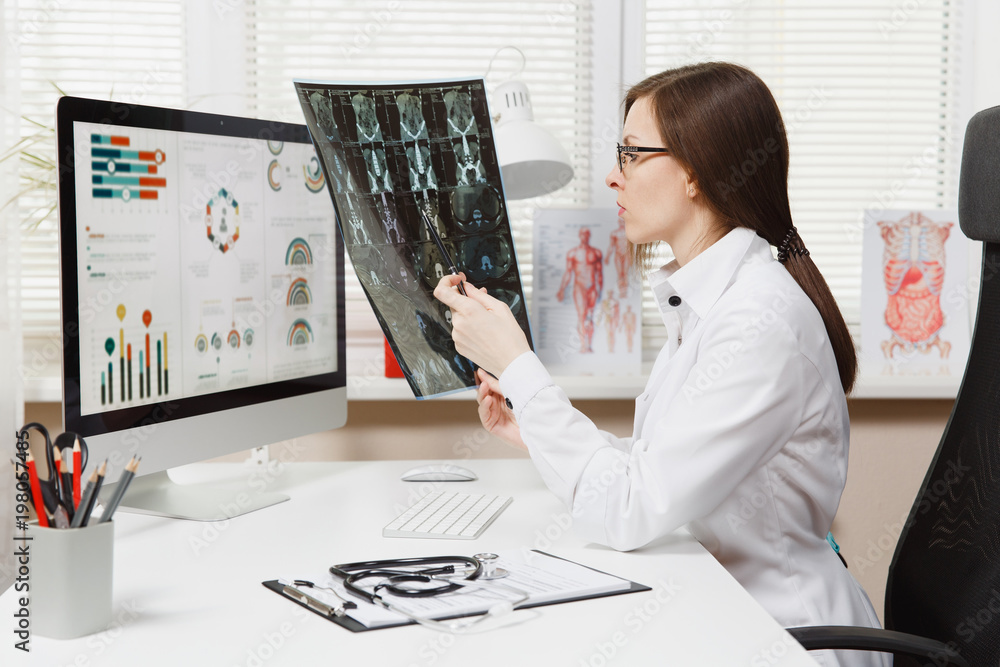 Female doctor sitting at desk with computer, film x-ray the brain by ...