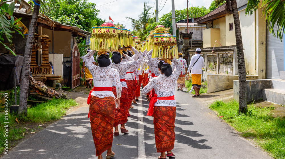 Balinese women in traditional costumes carry offerings to the temple ...