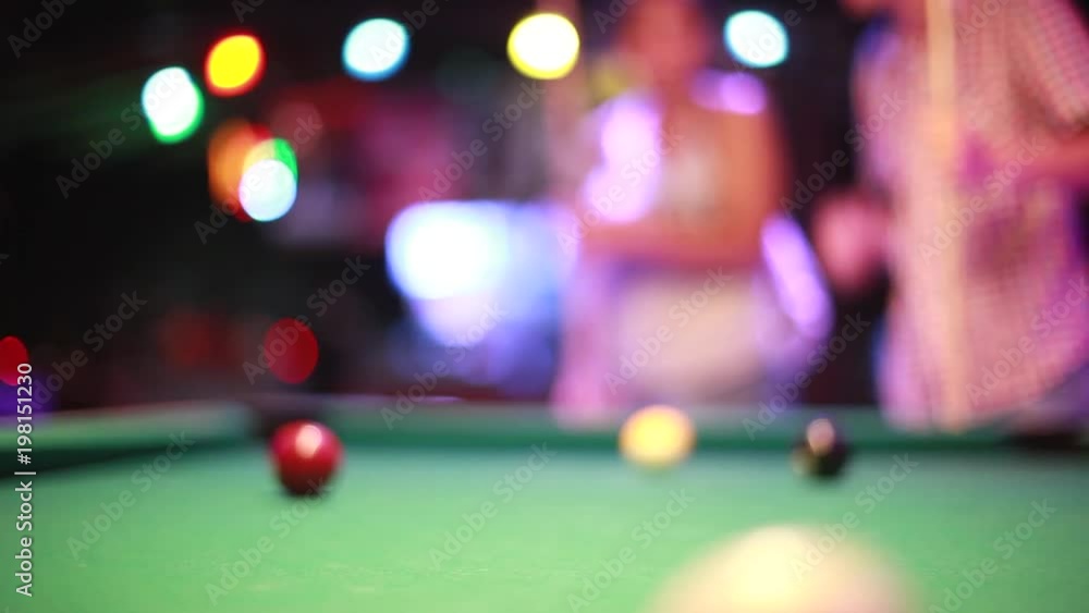 Playing pool billiards in a night bar with bokeh lights on the ...