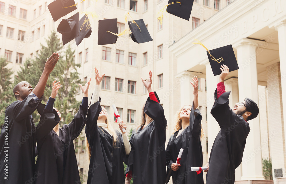 A group of graduates throwing graduation caps in the air Stock Photo ...