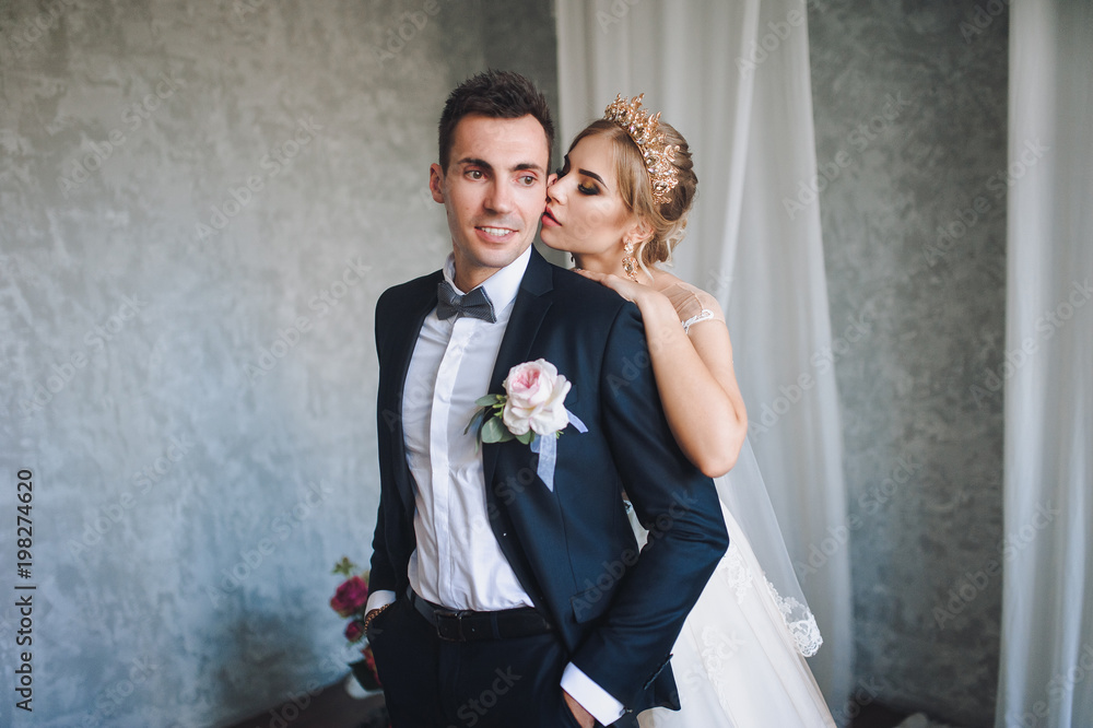 The bride is kissing the neck of her groom. The groom in a suit with a ...