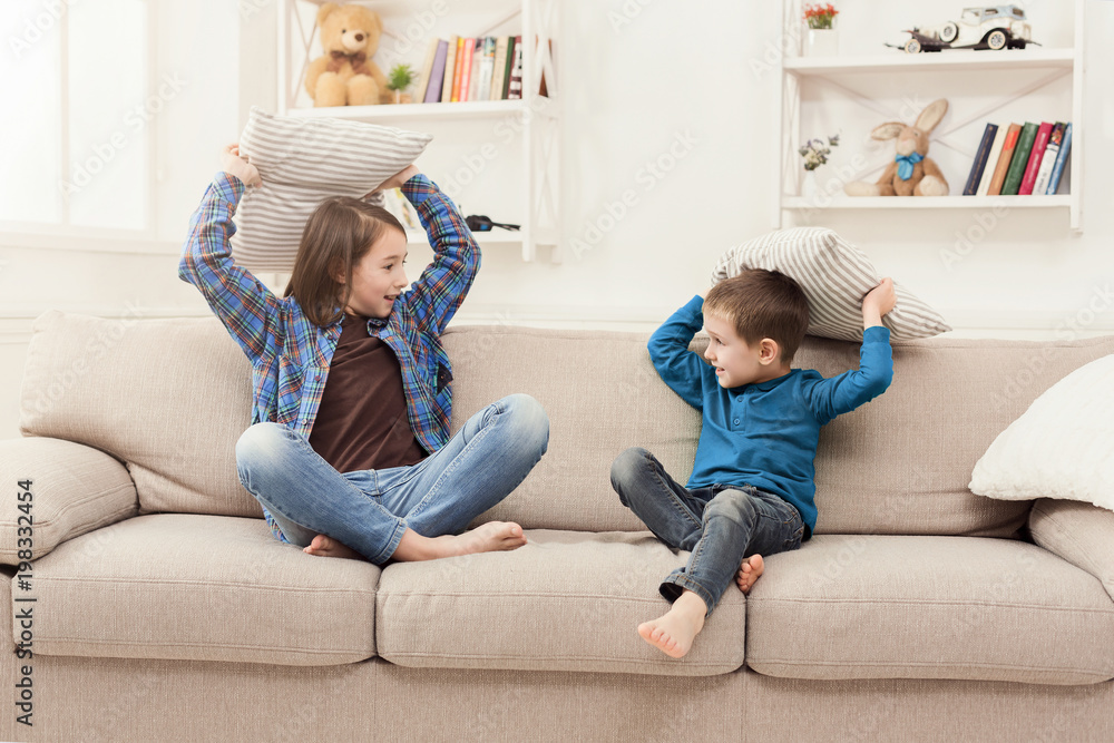 Brother and sister having pillow fight on sofa Stock Photo | Adobe Stock