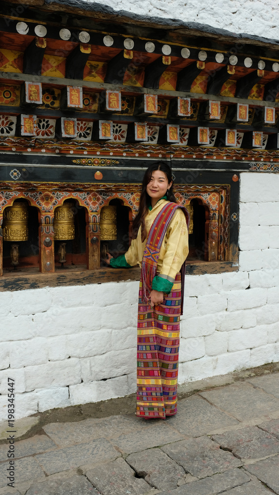 Bhutanese young woman facing the camera with a smile is wearing a kira ...