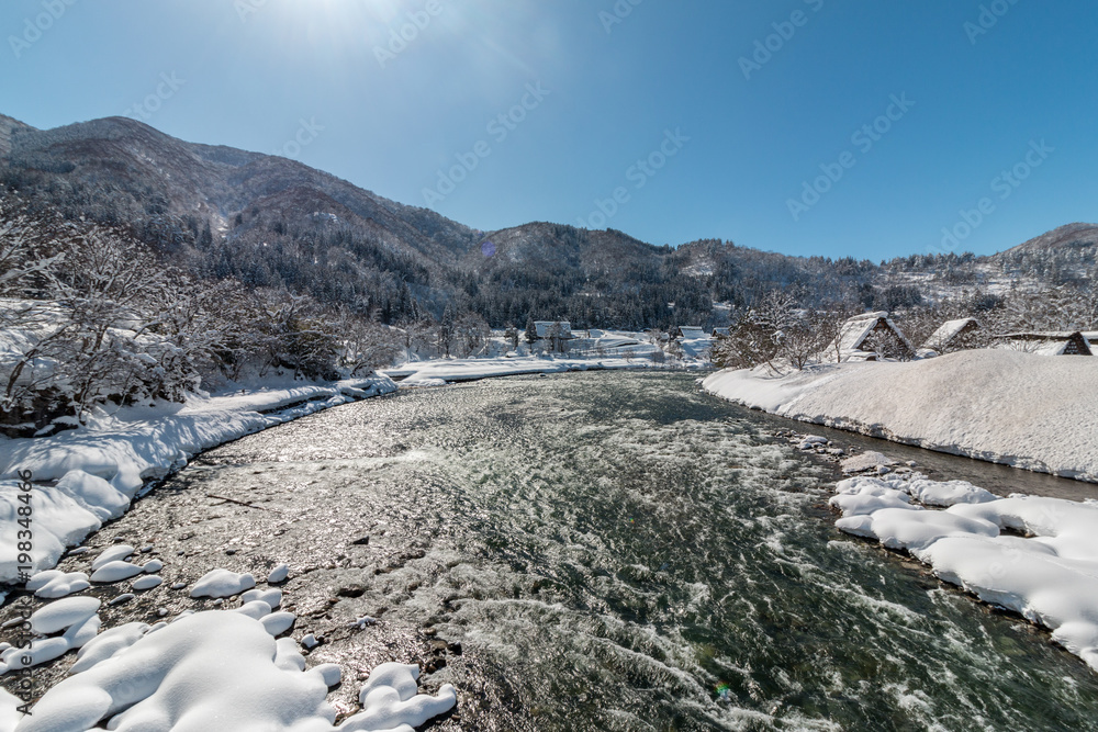 Shogawa river in Shirakawago village with snow covered ground ,blue sky ...