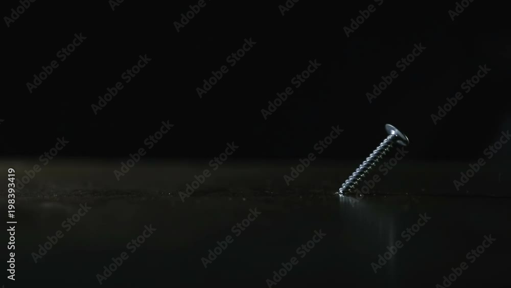 Screw is on a dark background. Hammer hits the screw, it bends. Close ...