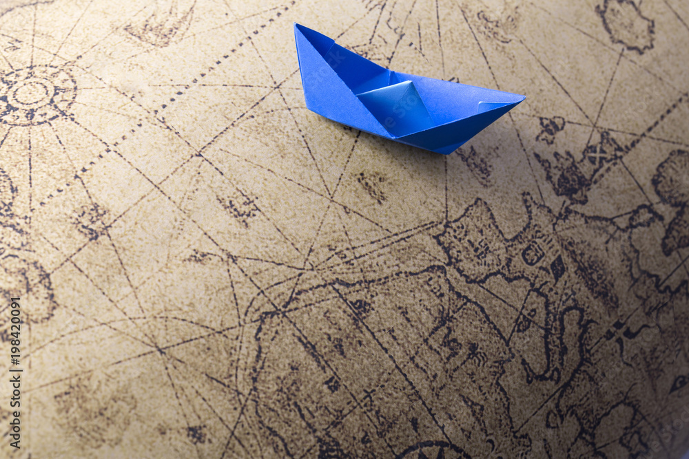 Blue paper ship isolated on old map background. Paper craft and origami ...
