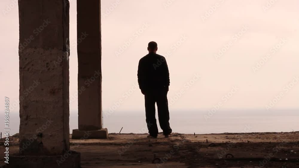Sad lonely man standing alone on edge of abandoned construction ...