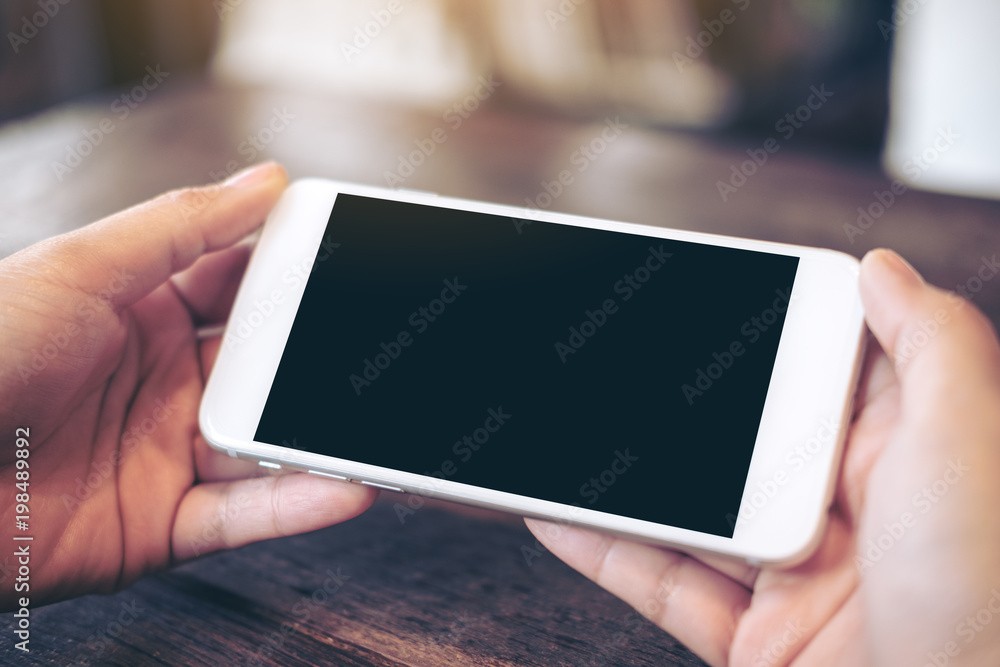 Mockup image of hands holding white mobile phone with blank black ...