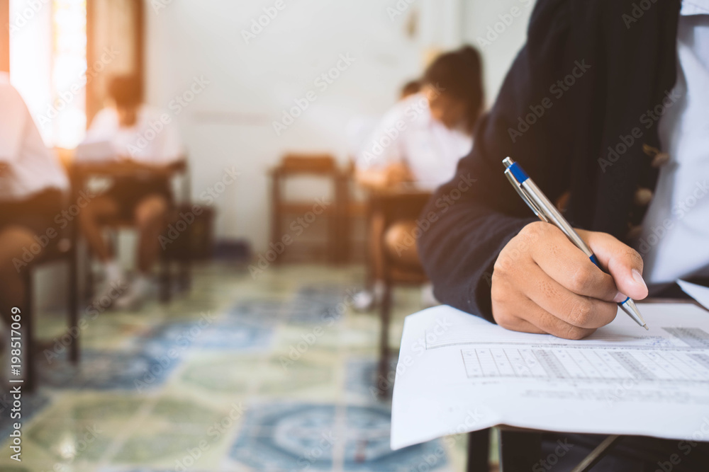 Students writing and reading exam answer sheets exercises in classroom ...