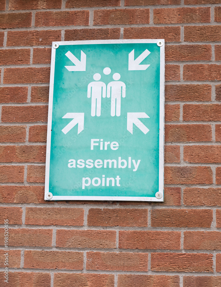 green and white fire assembly point sign on brick wall Stock Photo ...