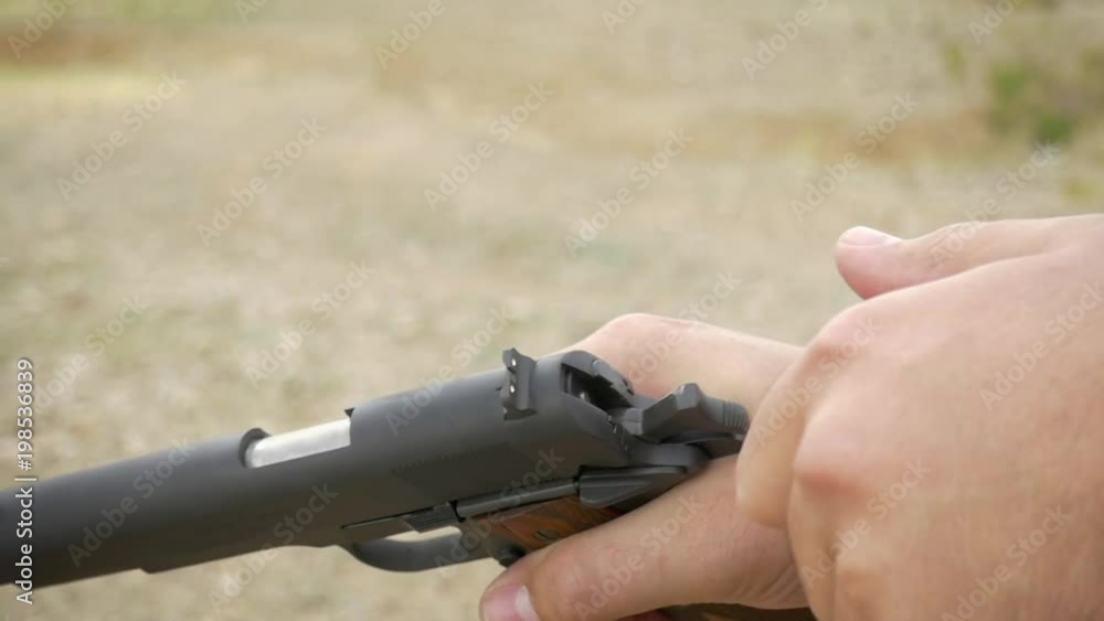 Man loading a handgun releases a round into the chamber in slow motion ...