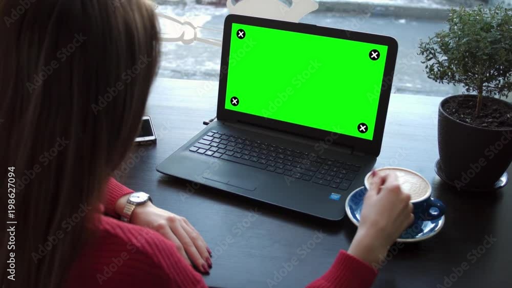 A Girl Looks at a Laptop With a Green Screen. The girl is watching her ...