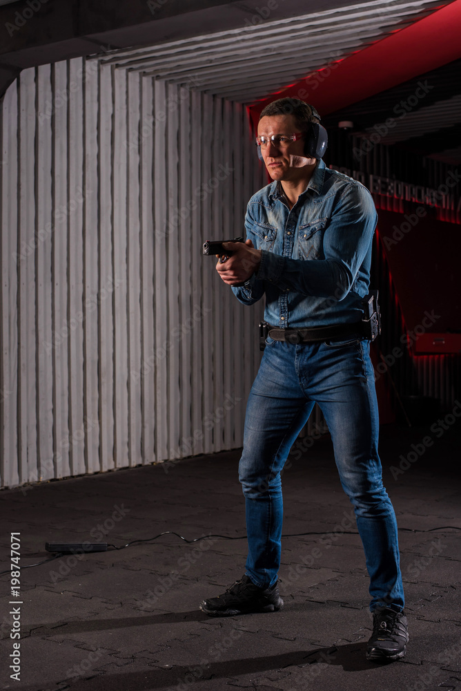 An adult man in jeans trains to shoot a gun in a closed dash. Stock ...