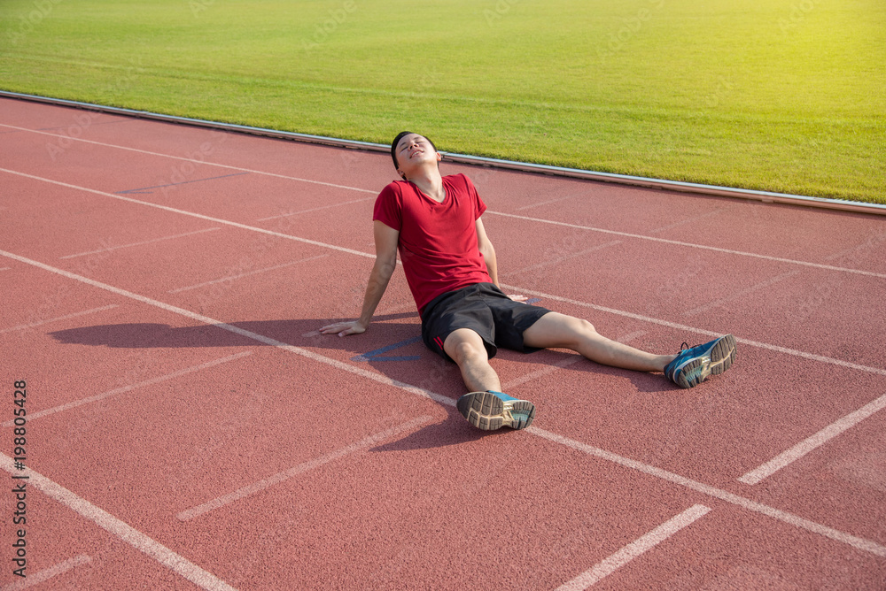 Young asian runner sitting on the ground after losing in competition ...
