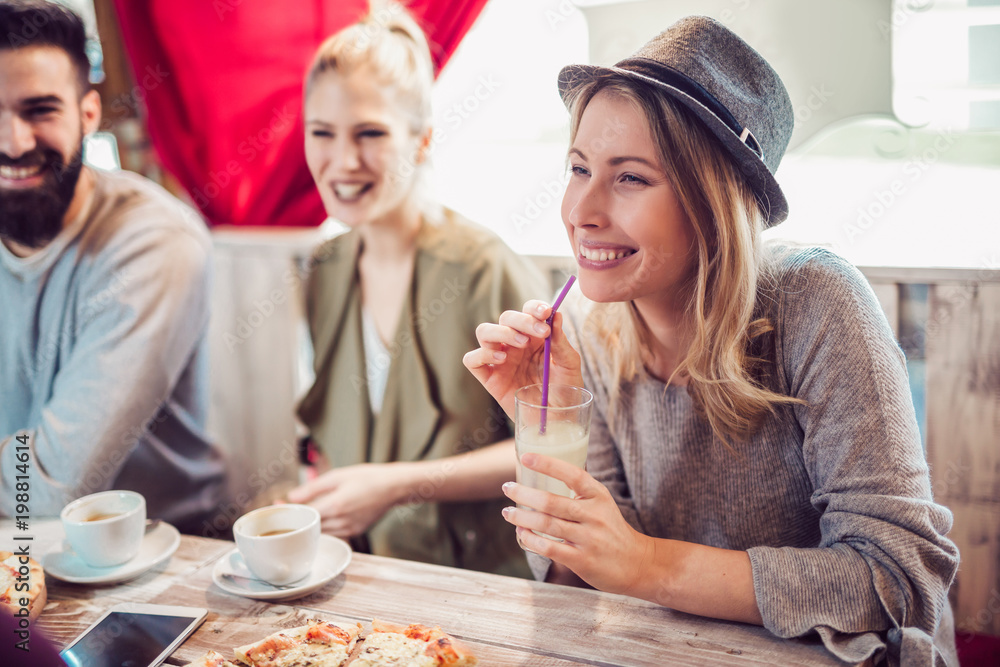 Young friends sharing pizza in a indoor cafe Stock Photo | Adobe Stock