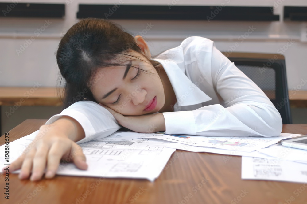 Tired overworked young Asian business woman lying down on the desk in ...