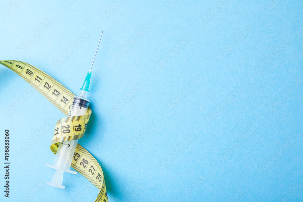 Syringe with a needle and yellow measuring tape. Injections for body ...