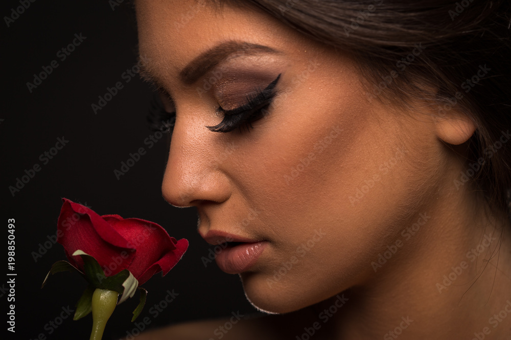 Beautiful young woman smelling a red rose Stock Photo | Adobe Stock