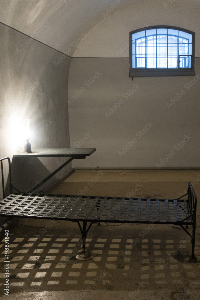 The old prison cell in which the bed, table, lamp, window with a ...