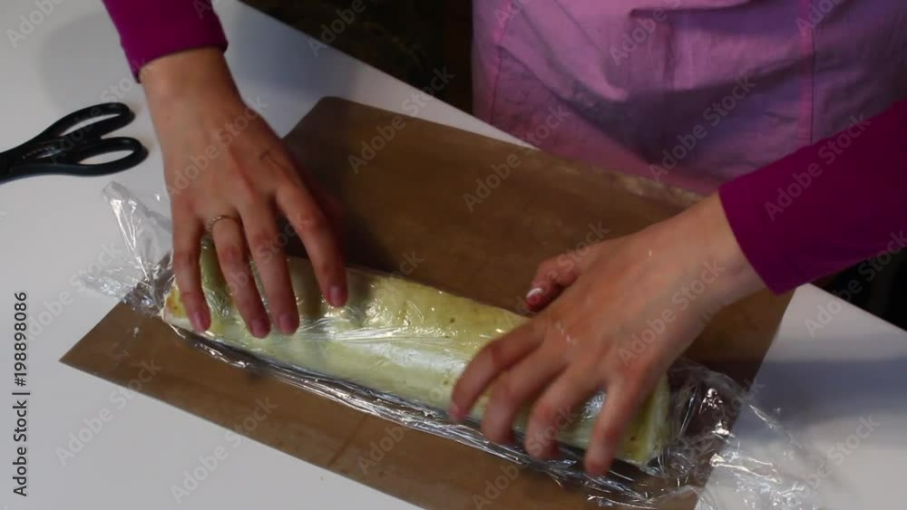 A woman wraps a fresh roll in a plastic wrap so that it takes shape and ...