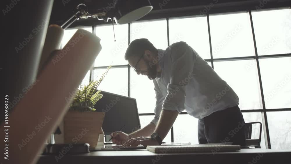 Bearded young businessman working on modern loft office. Man standing ...