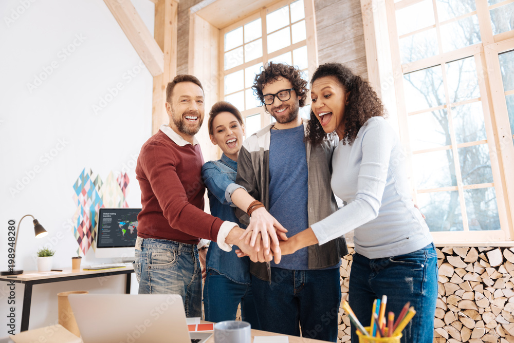 We are team. Good-looking alert young employees smiling and holding ...