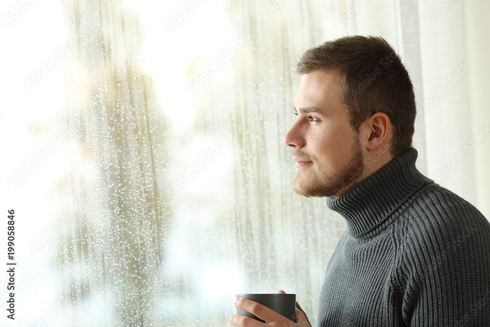 Happy man looking through a window in a rainy day Stock Photo | Adobe Stock