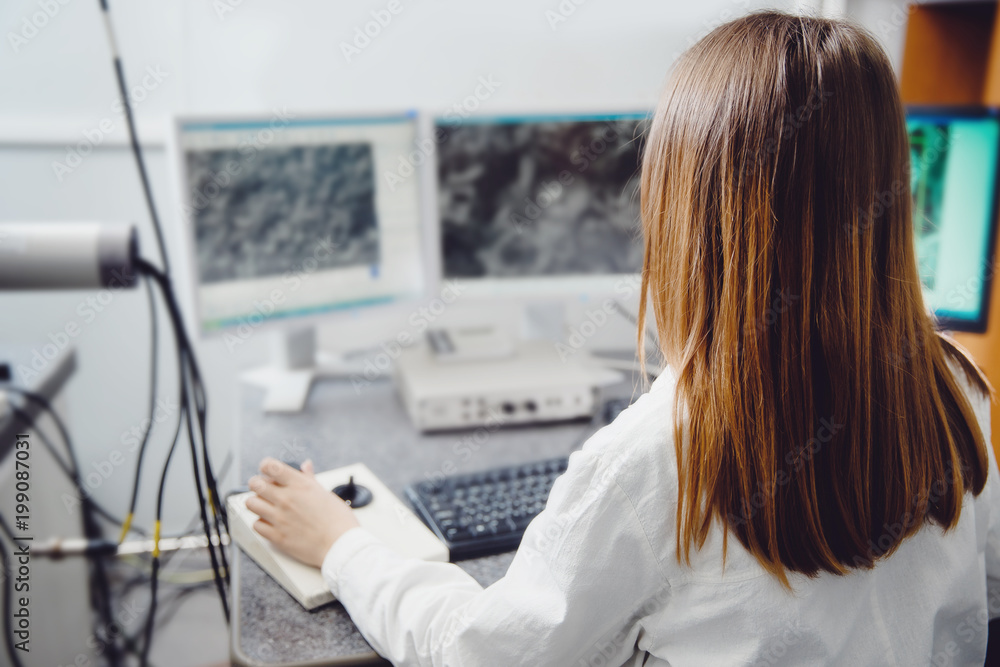Back view. Young female student is an engineer working on computers ...