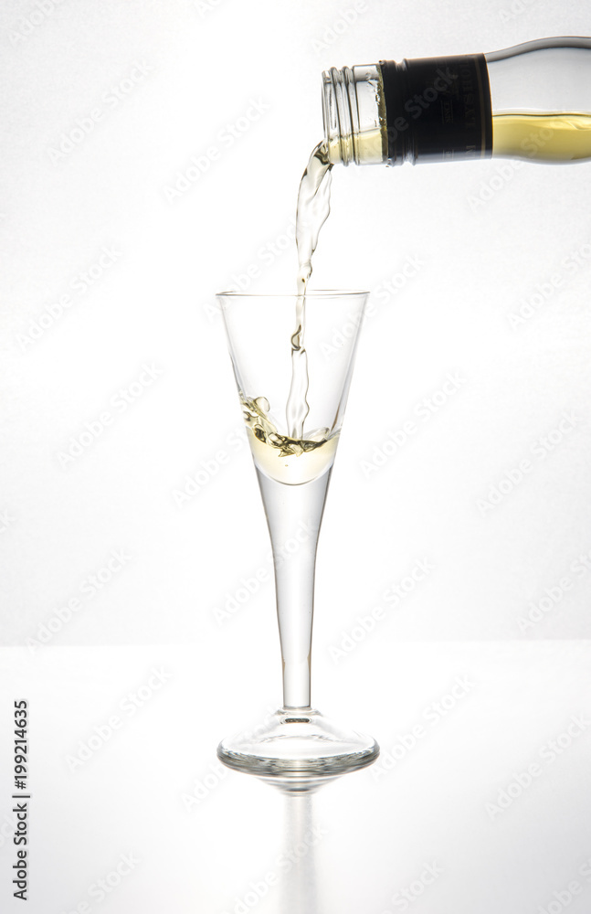 Ett snapsglas i silhuett flylls hastigt med en varmgul och kall snaps ...