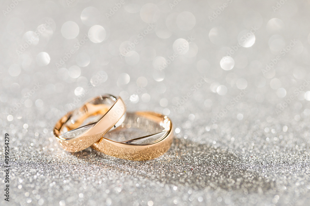 Silver sparkling glitter bokeh background with golden wedding rings ...