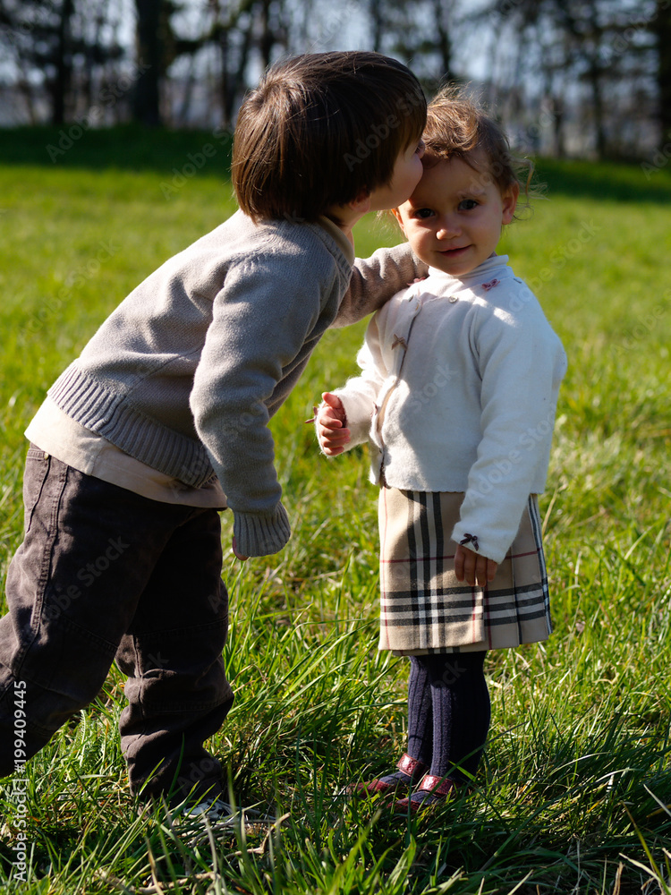 portrait of two male and female siblings, 3 and 5 years old, kissing ...