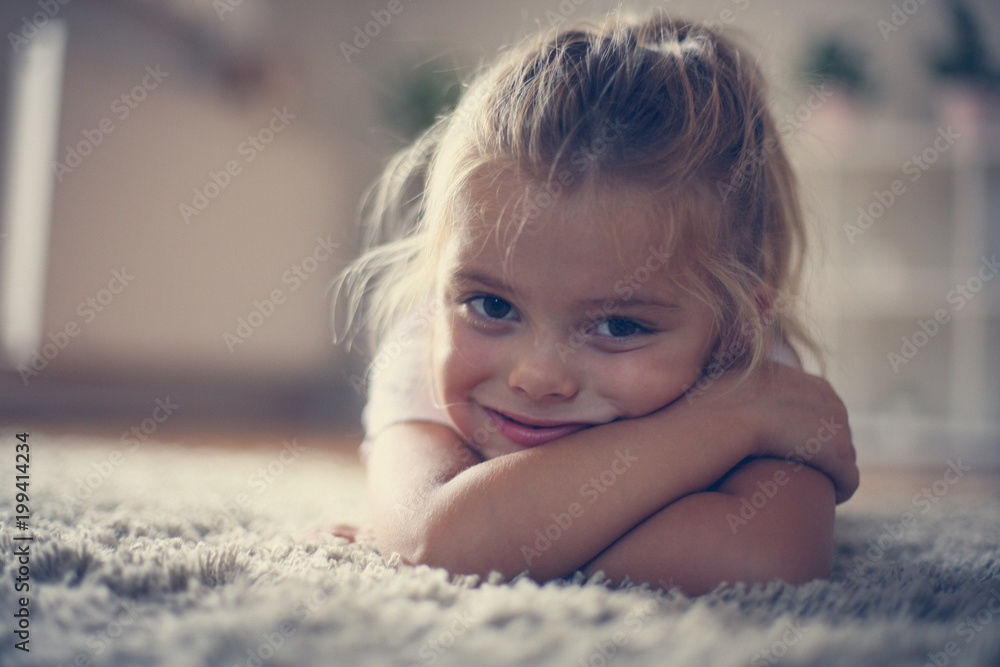 Little girl looking at camera. Little girl at home , lying on floor and ...