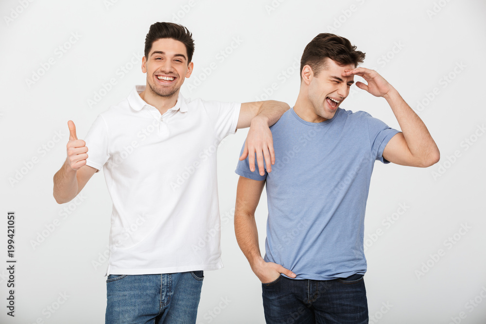 Two handsome men pals 30s wearing casual t-shirt and jeans smiling and ...