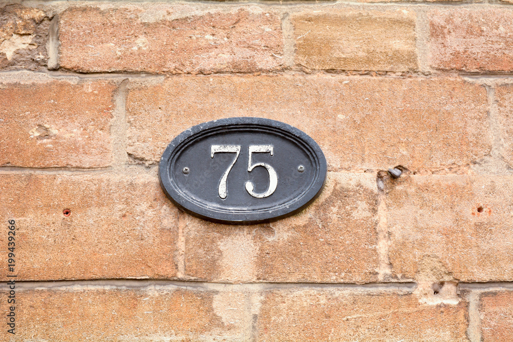 House number 75 sign fixed to brick wall Stock Photo | Adobe Stock