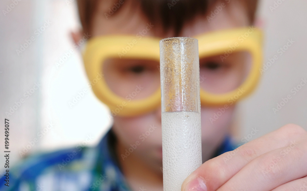 Experiments on chemistry at home. Smiling boy is looking at chemical ...