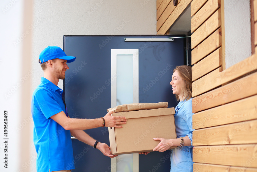 Smiling delivery man in blue uniform delivering parcel box to recipient ...