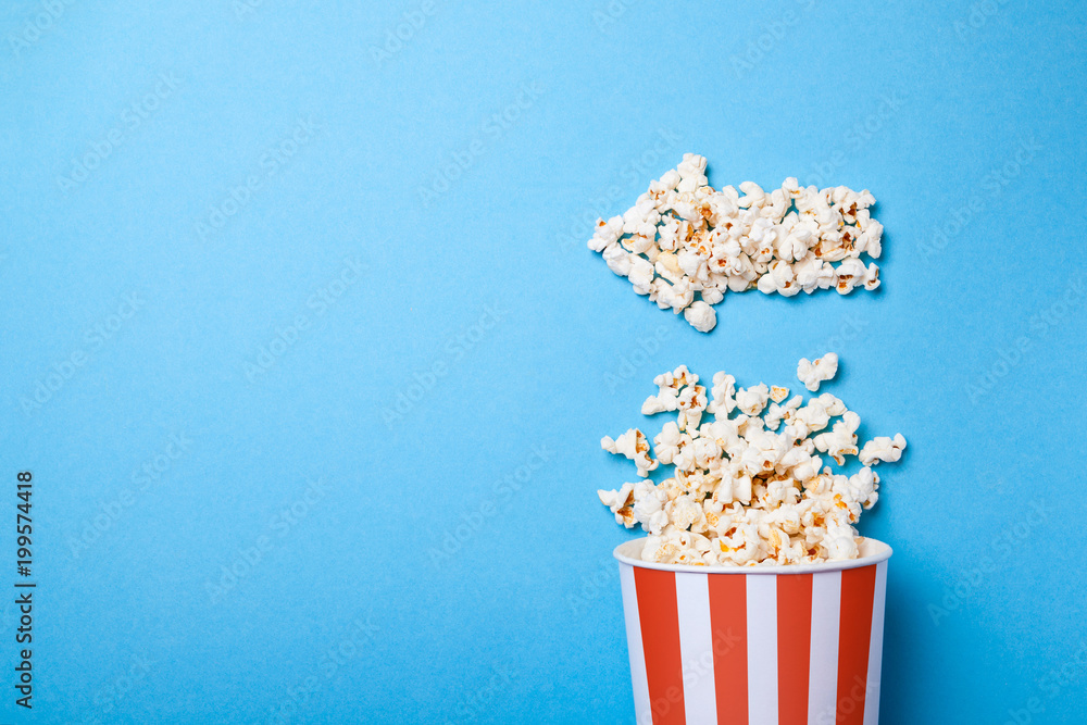 Spilled popcorn in the form of an arrow to the left and paper bucket in ...