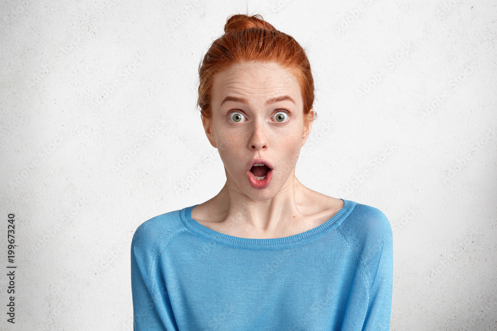 Scared ginger female stares at camera with bugged eyes and widely ...