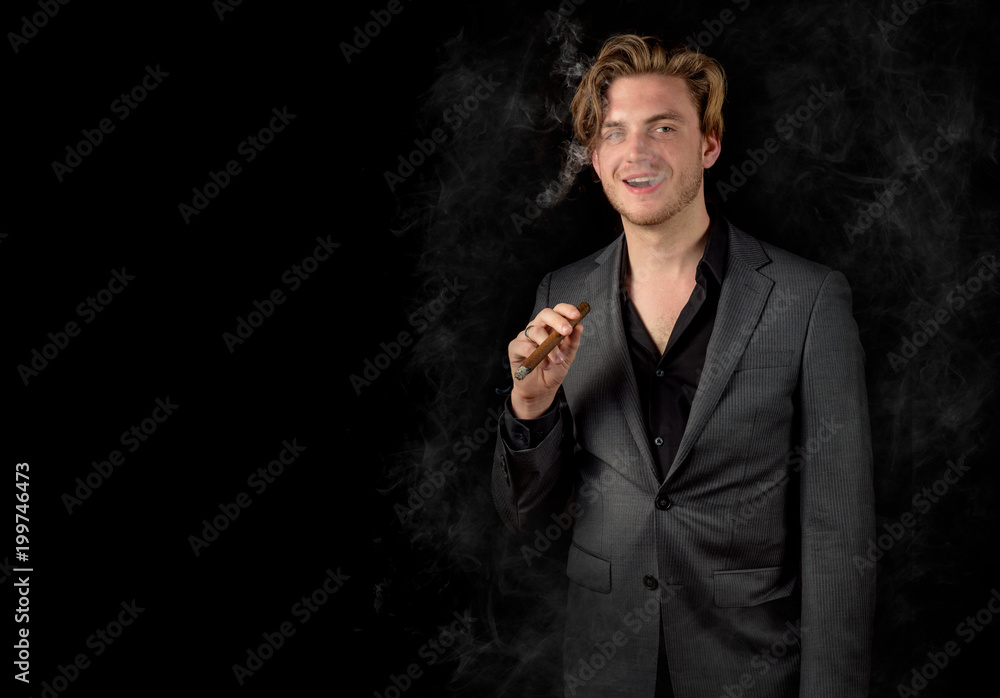 Male model in a classy dark suit isolated against a black background ...