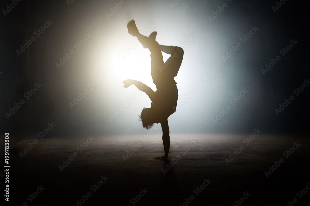 man showing a one-handed handstand with legs on the bright stage. kind ...