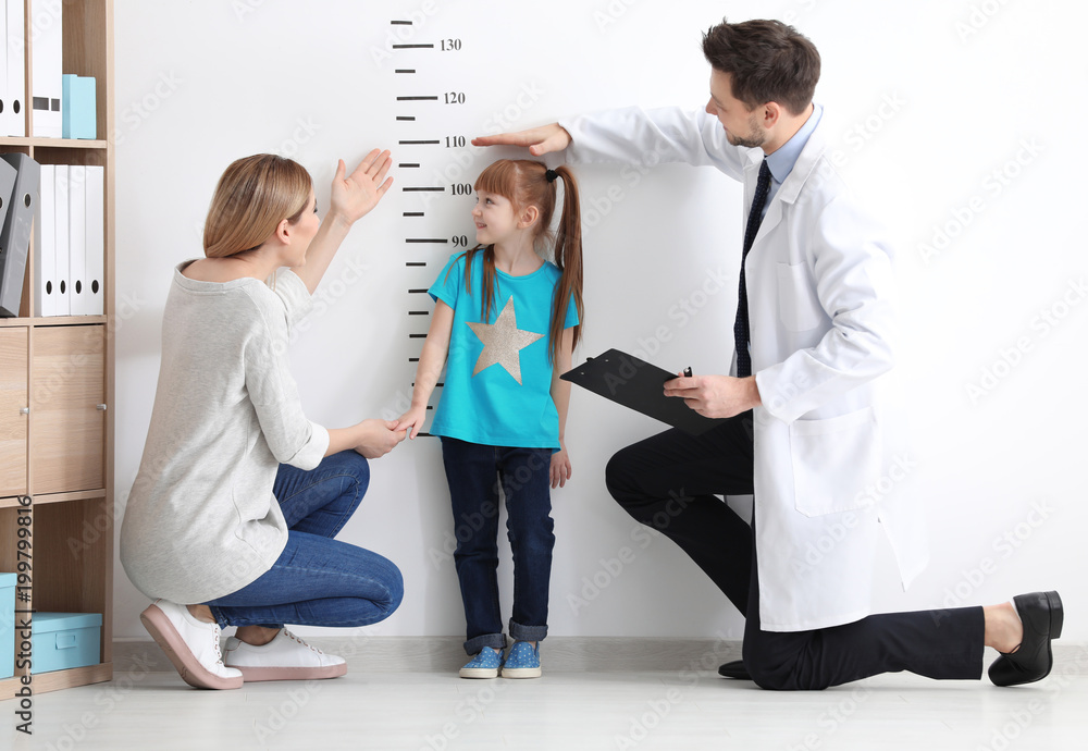 Male doctor measuring height of little girl in clinic Stock Photo ...