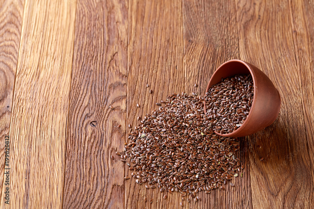 An overturned ceramic bowl with linseeds on a rustic background, close ...